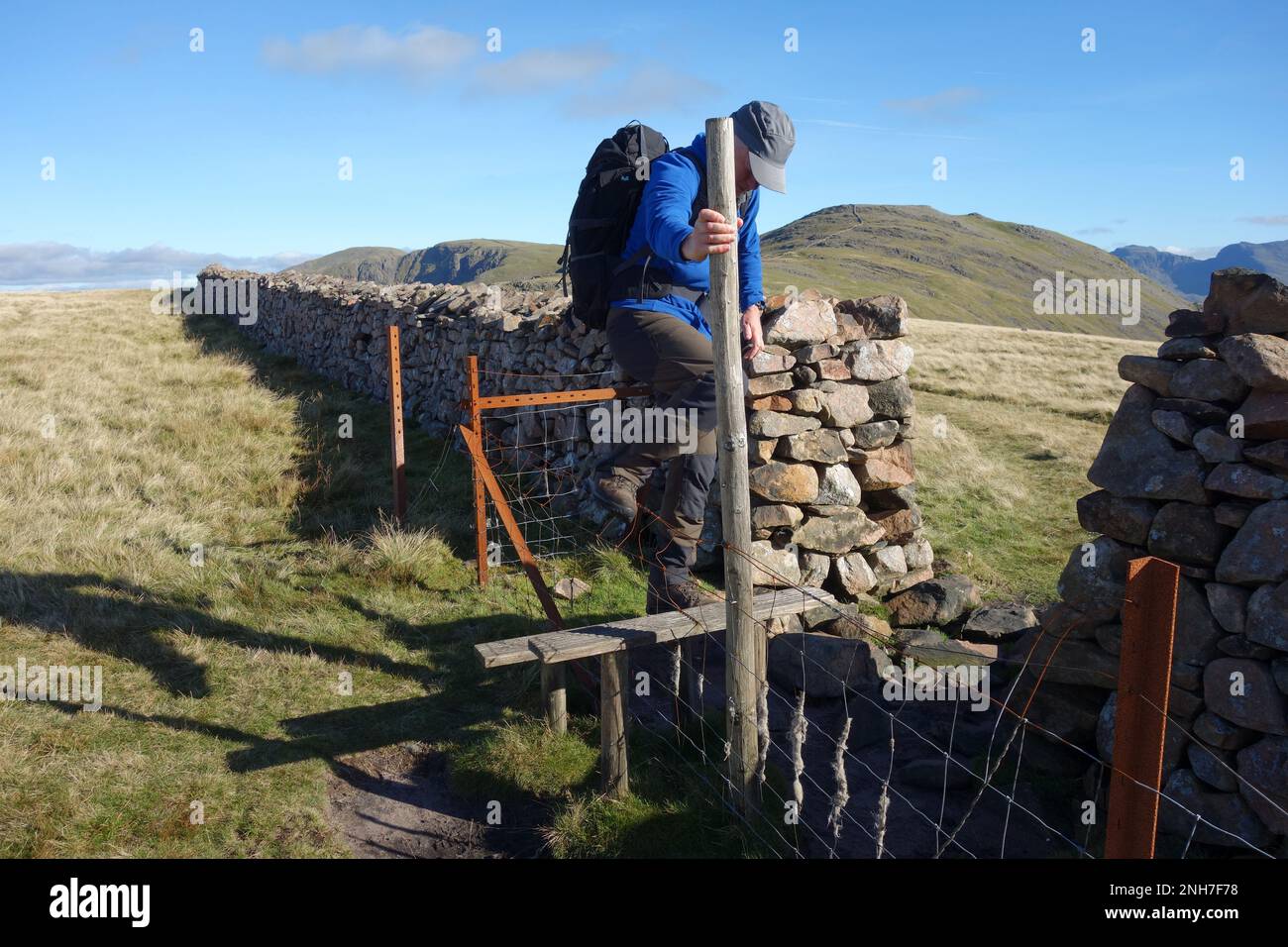 Man Climbing a Wooden Stile in a Stone Wall om the Summit of the ...