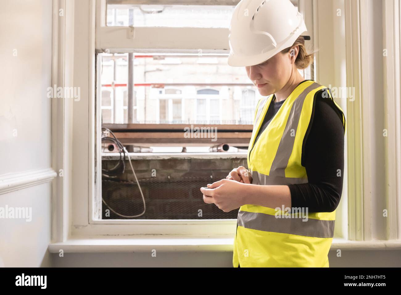 Civil engineer woman using a calculator in front of a window in a ...