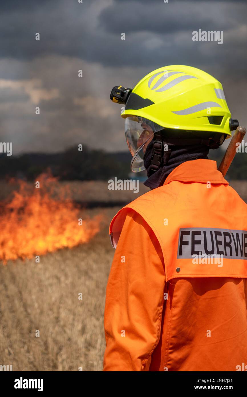 A professional firefighter wearing an orange protective suit standing ...