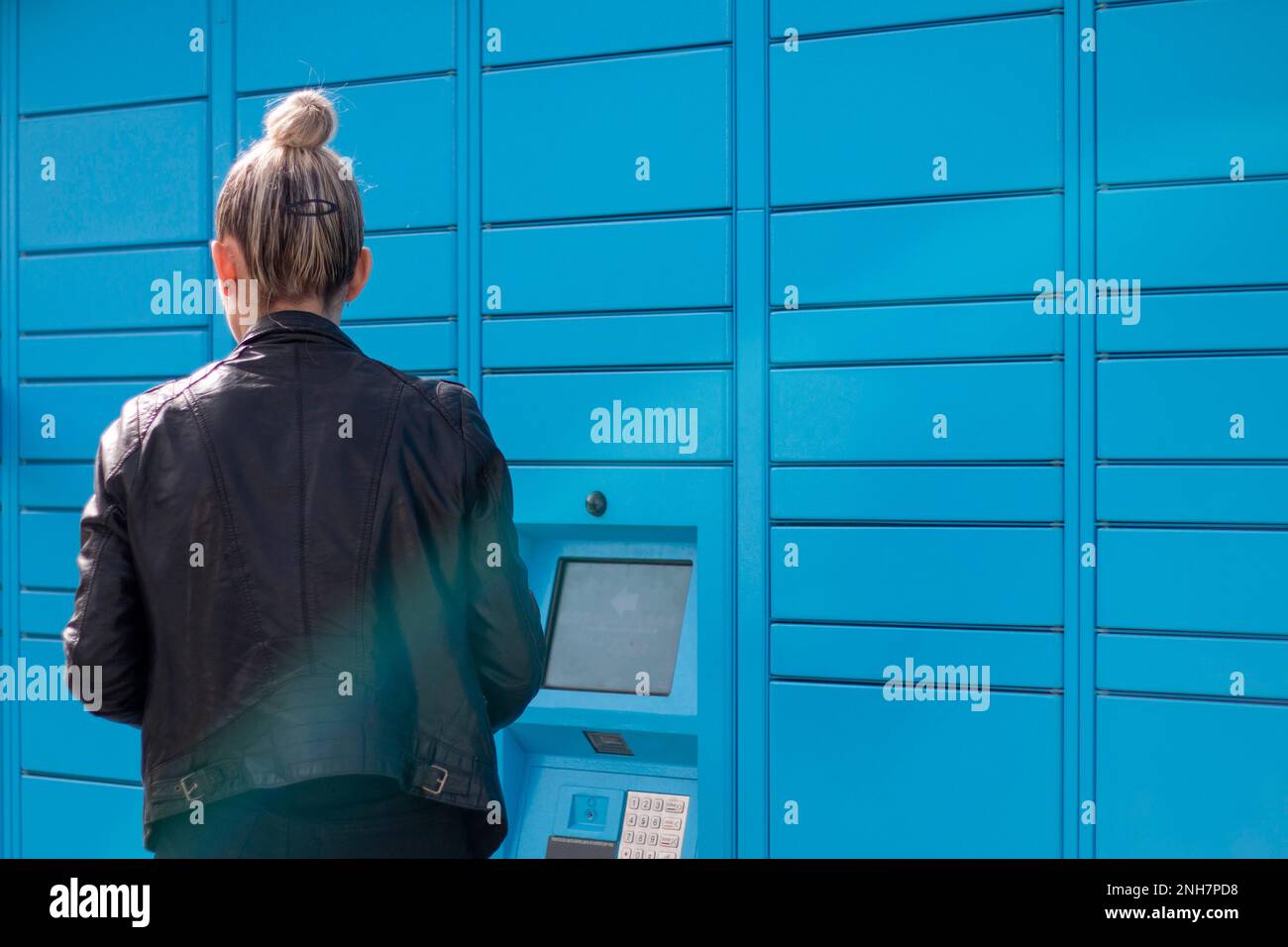Blonde woman in a black leather jacket picking up a package in a ...