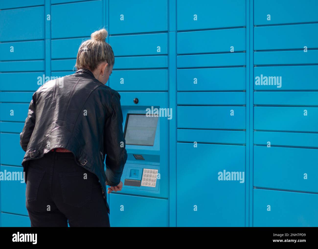 Blonde woman in a black leather jacket picking up a package in a ...