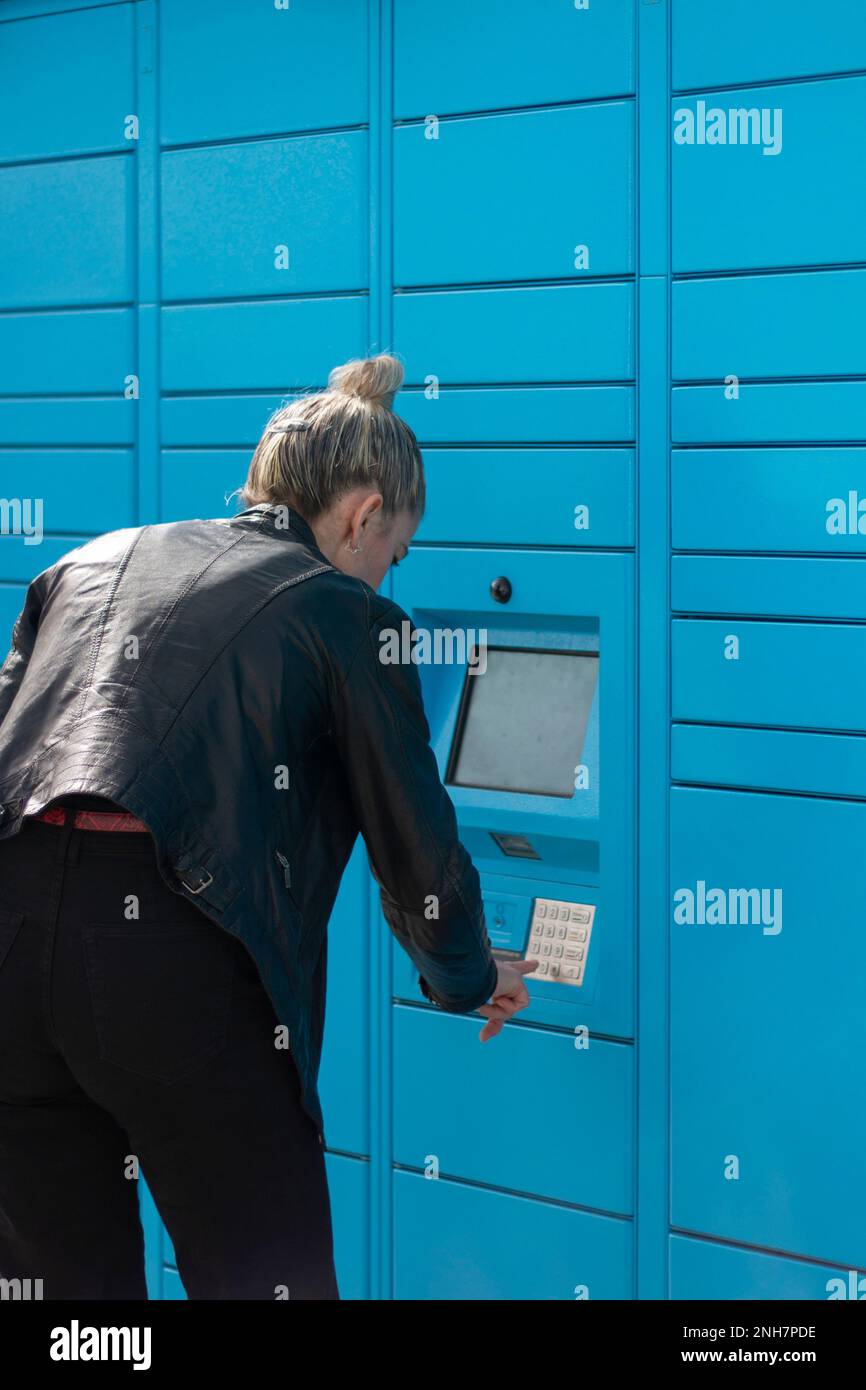 Blonde woman in a black leather jacket picking up a package in a ...
