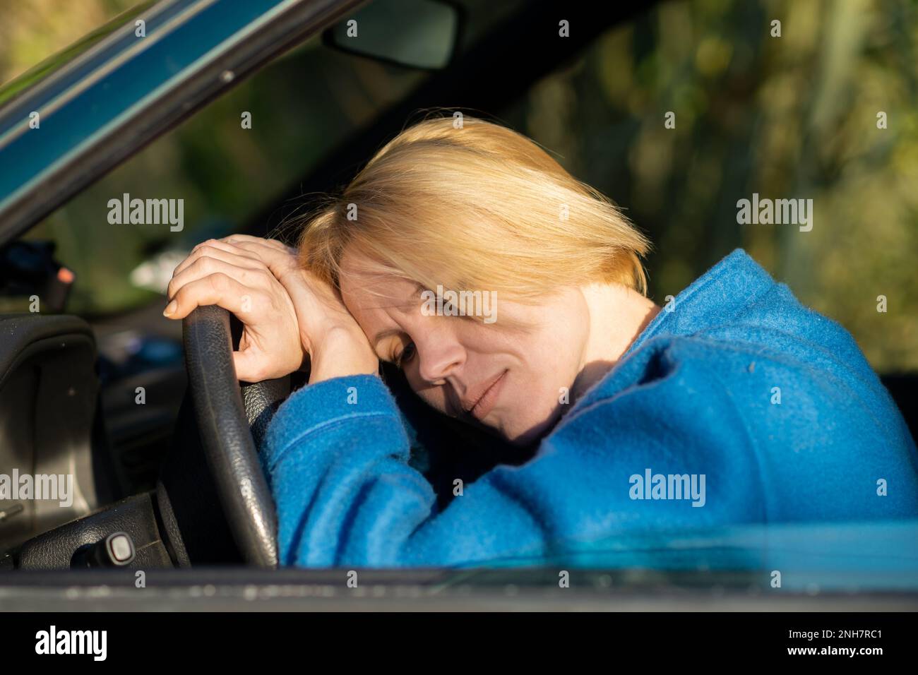 Tired woman driving a car. A middle-aged woman in her forties leaned ...