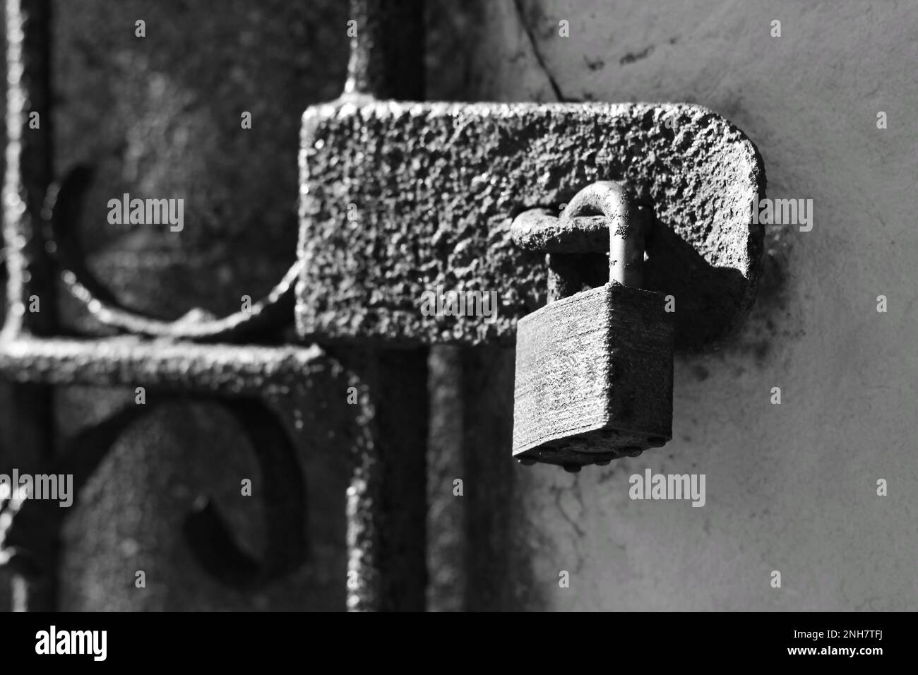 Vintage traditional metal padlock keeping an old gate closed in a black ...