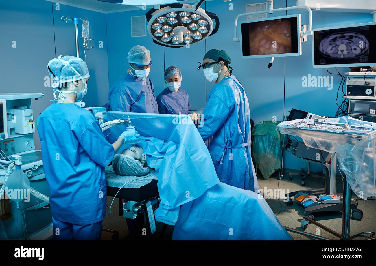 Surgeons working on patient in modern operating room of hospital ...