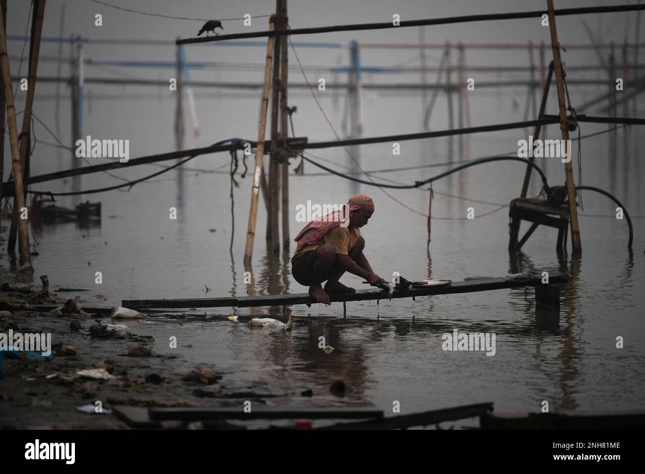 A man cleans fish after catching it in the river Brahmaputra in ...