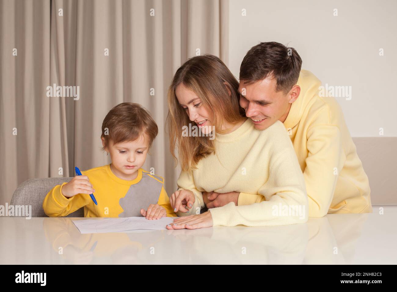 Adorable smiling family, parents in yellow clothes with their child son ...