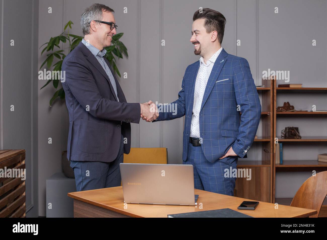 Two successful businessman in suit making handshake because of ...