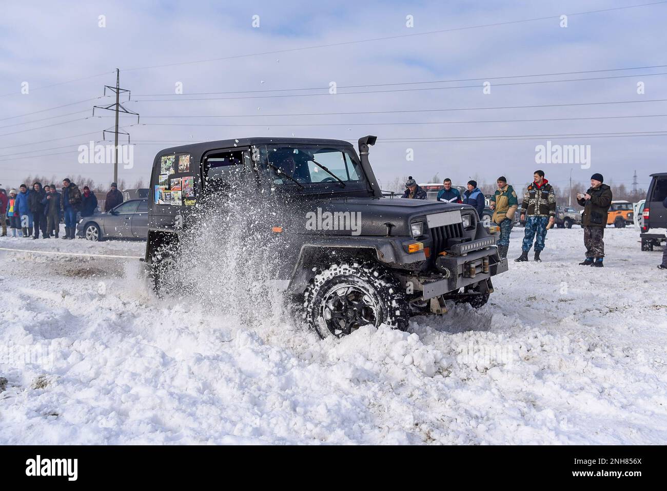 An old Jeep Wrangler skids in the snow among a crowd of people at an ...