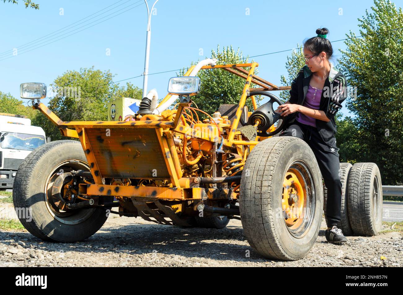 Brunette girl in costume "Adidas" interested sits in a small, off-road ...