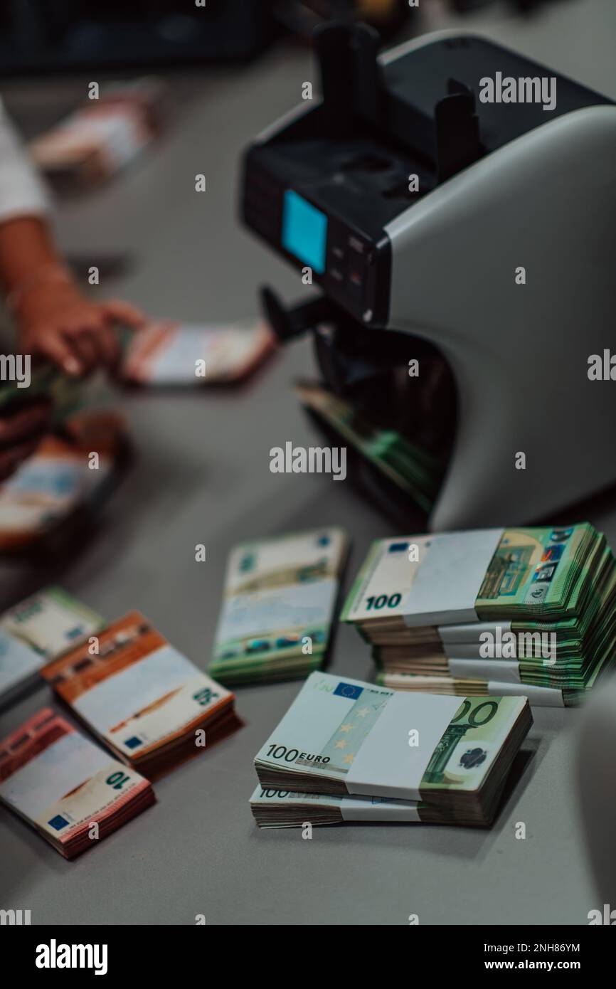 Bank employees using money counting machine while sorting and counting ...