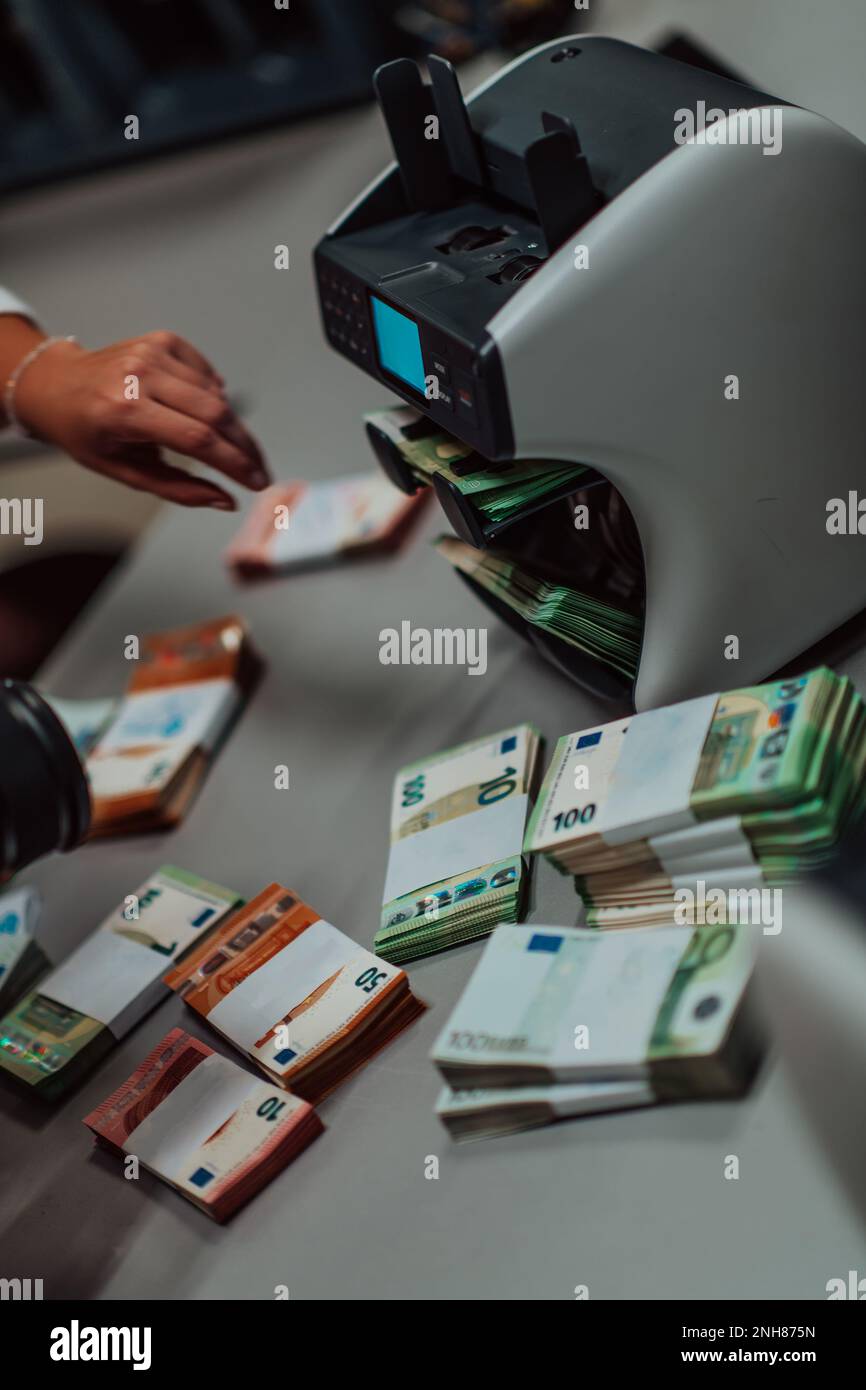 Bank employees using money counting machine while sorting and counting ...