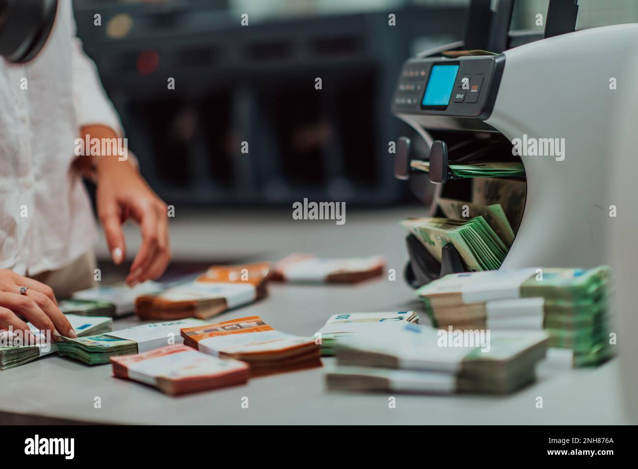 Bank employees using money counting machine while sorting and counting ...