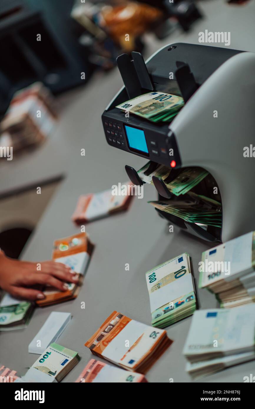 Bank employees using money counting machine while sorting and counting ...