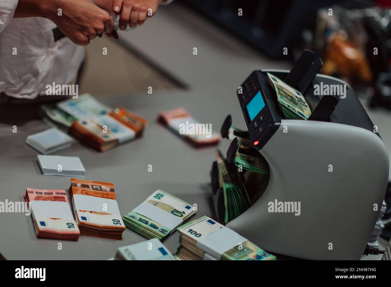 Bank employees using money counting machine while sorting and counting ...