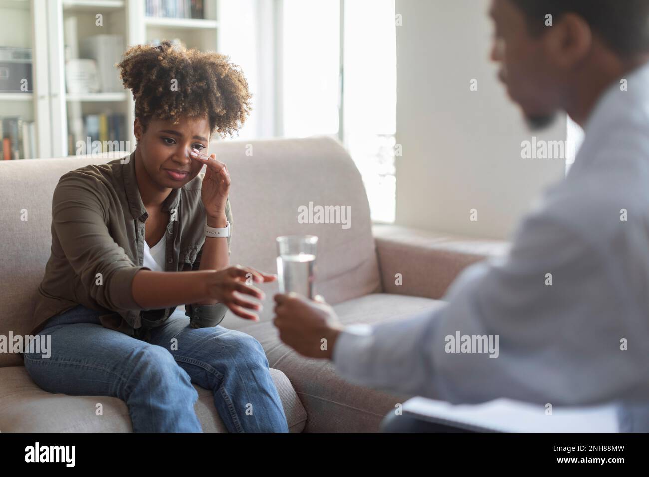 Black man psychologist giving glass of water to crying woman Stock ...