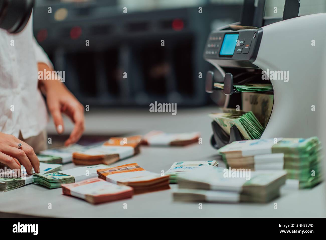 Bank employees using money counting machine while sorting and counting ...