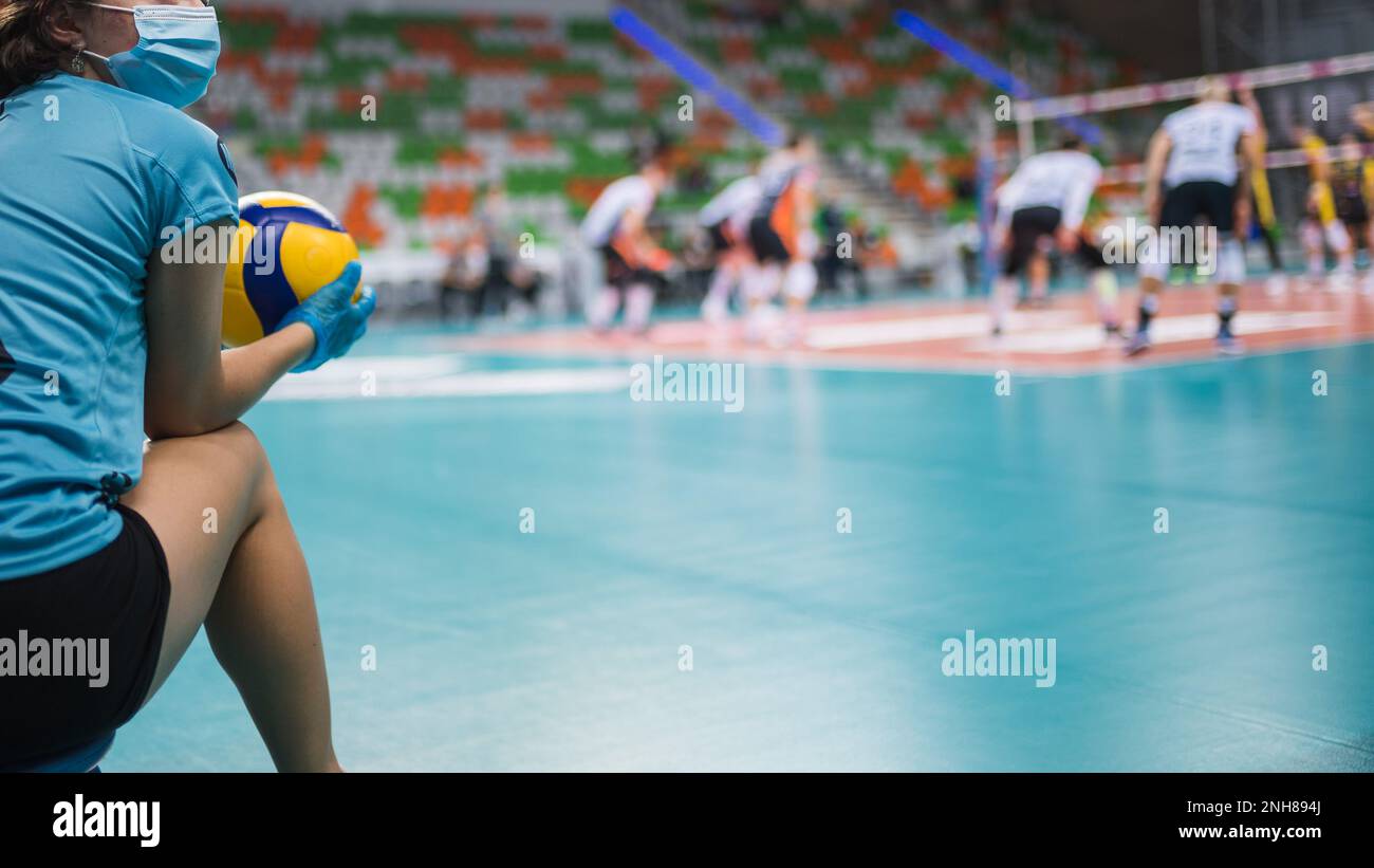 Girl with face mask and voleyball ball in the hands in the background ...