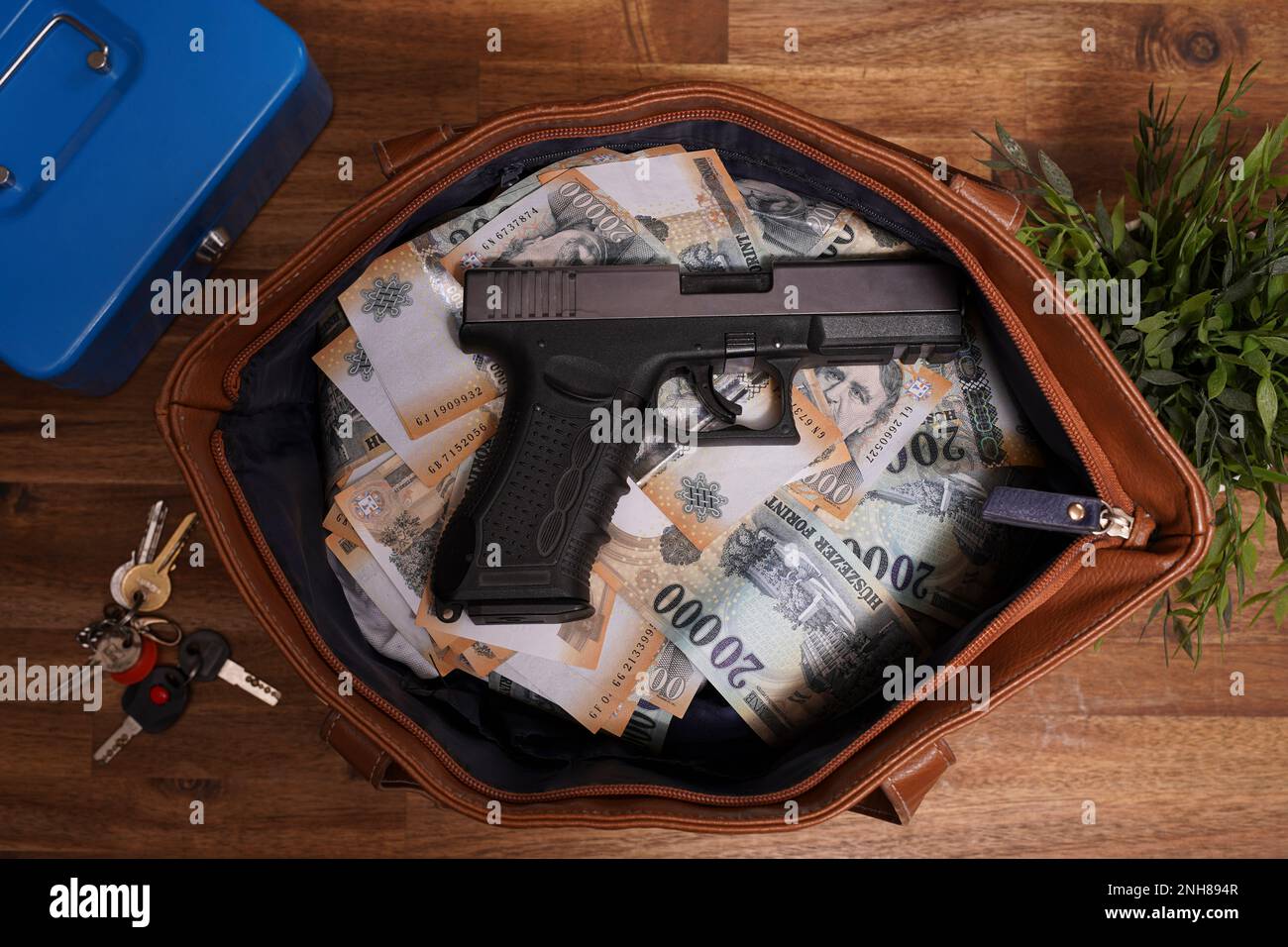 Travel bag with lots of money and gun. On the table is a safe, key and ...