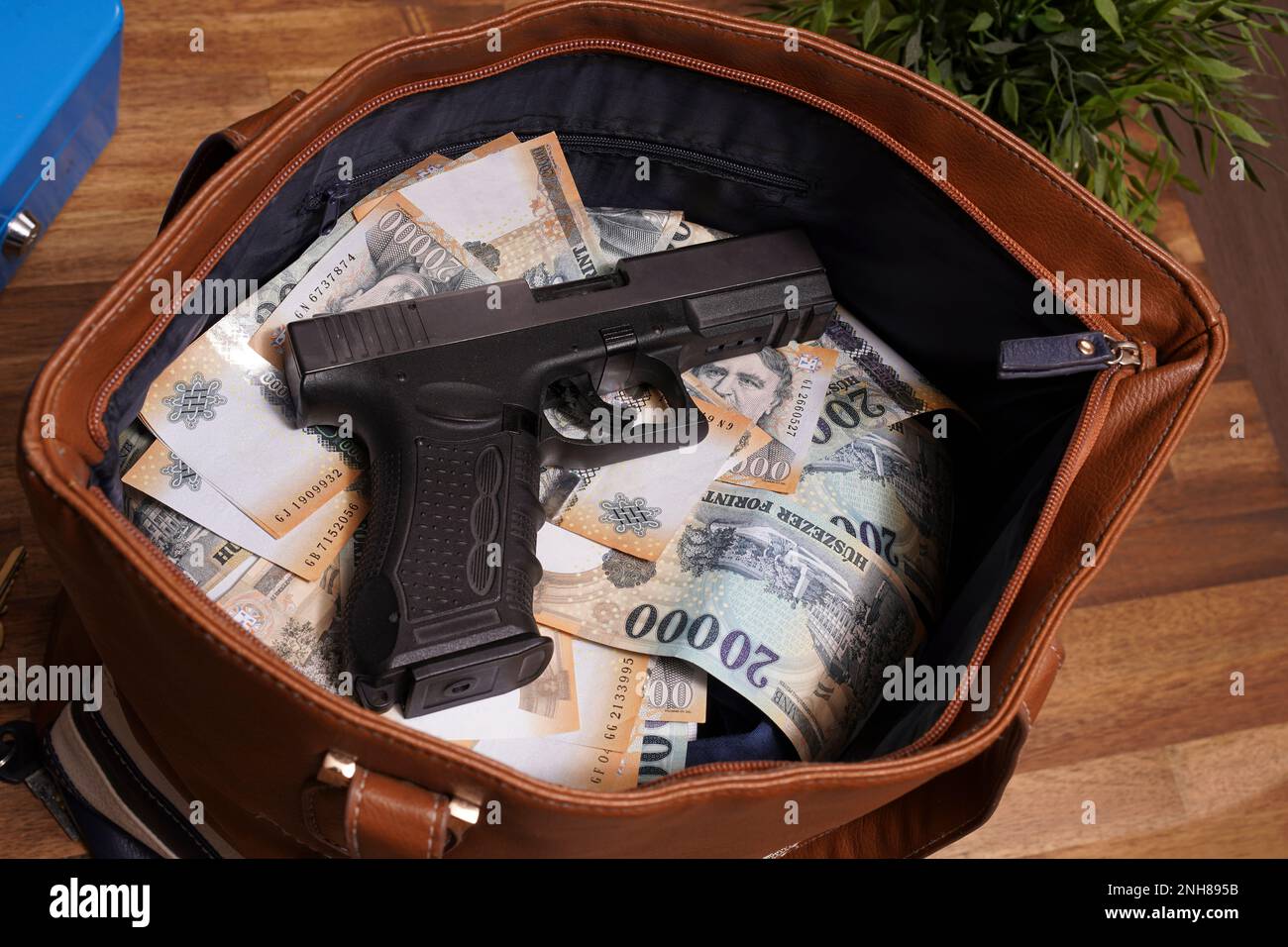 Travel bag with lots of money and gun. On the table is a safe, key and ...