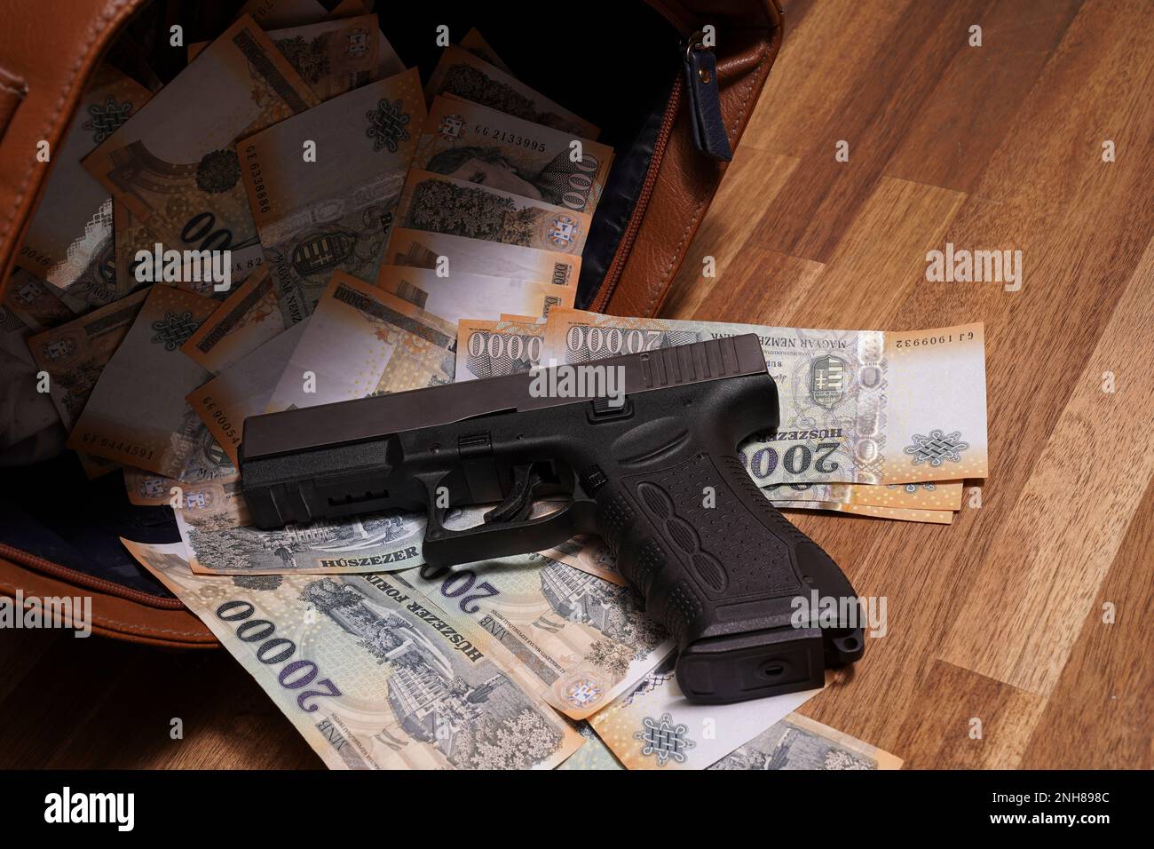 Travel bag with lots of money and gun. On the table is a safe, key and ...