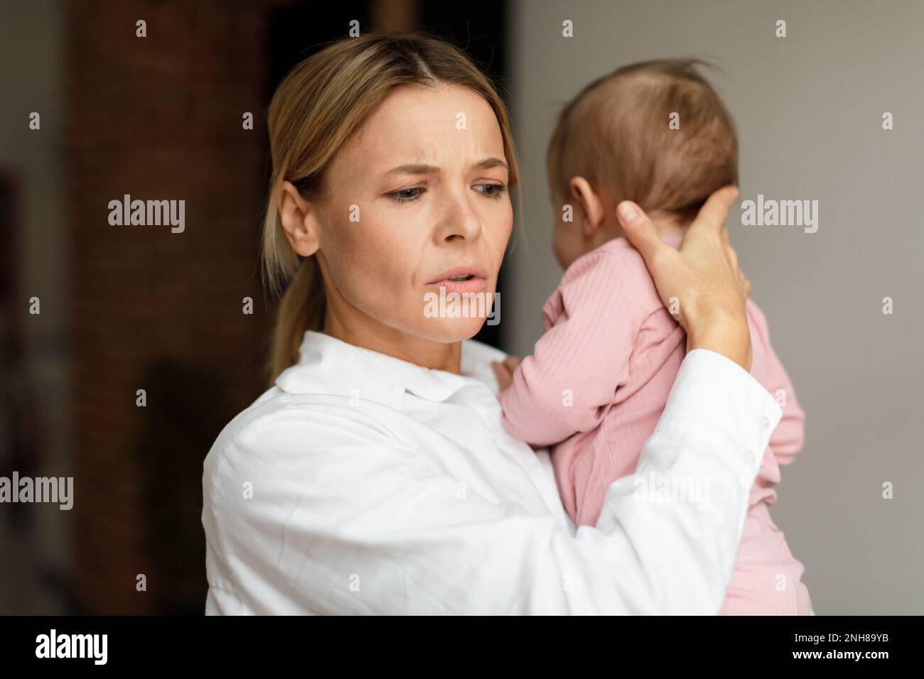 Maternity concept. Worried mother holding her baby on hands, kid crying ...