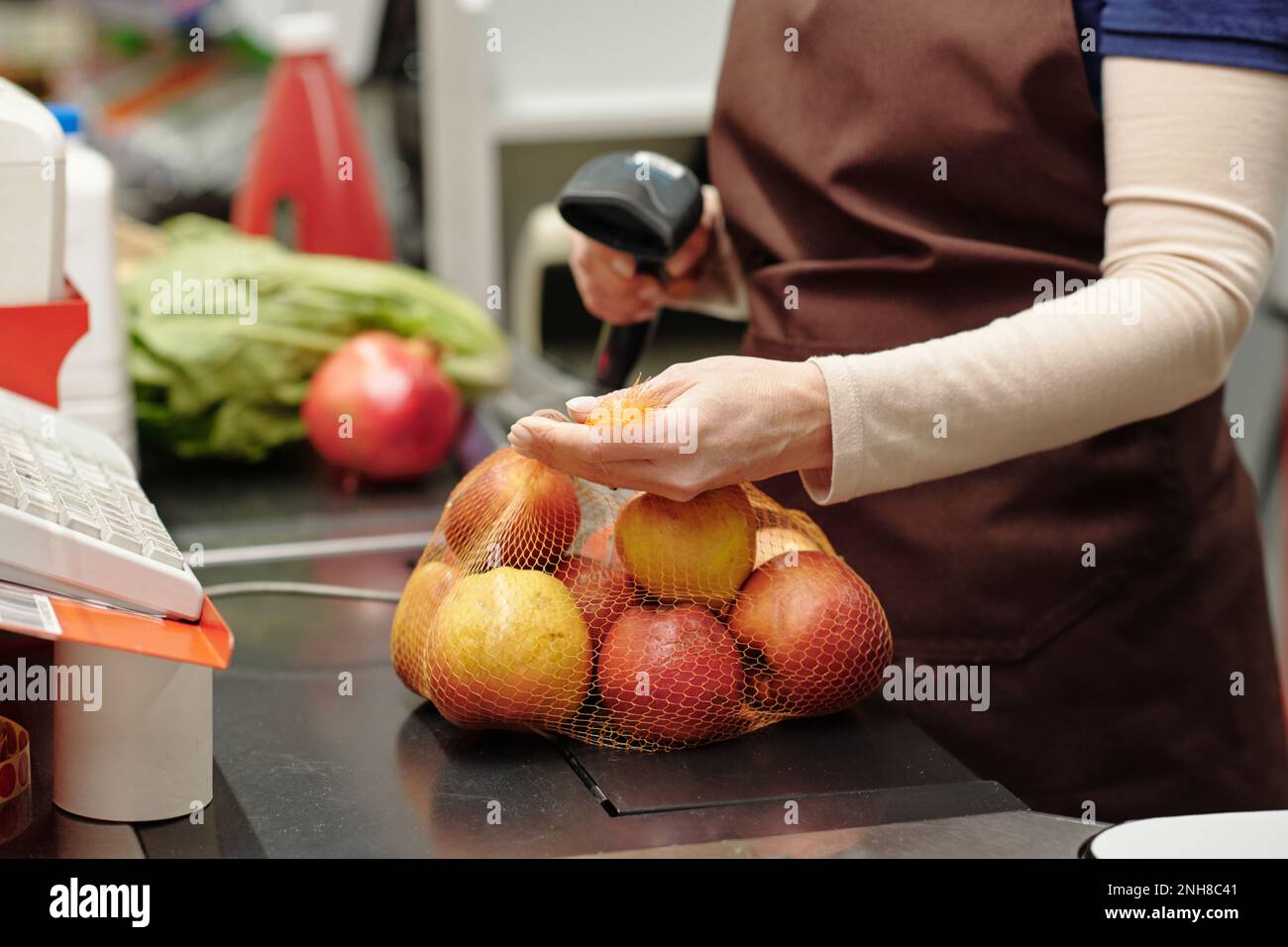 Close-up of female cashier scanning cost label on pack of red ripe ...