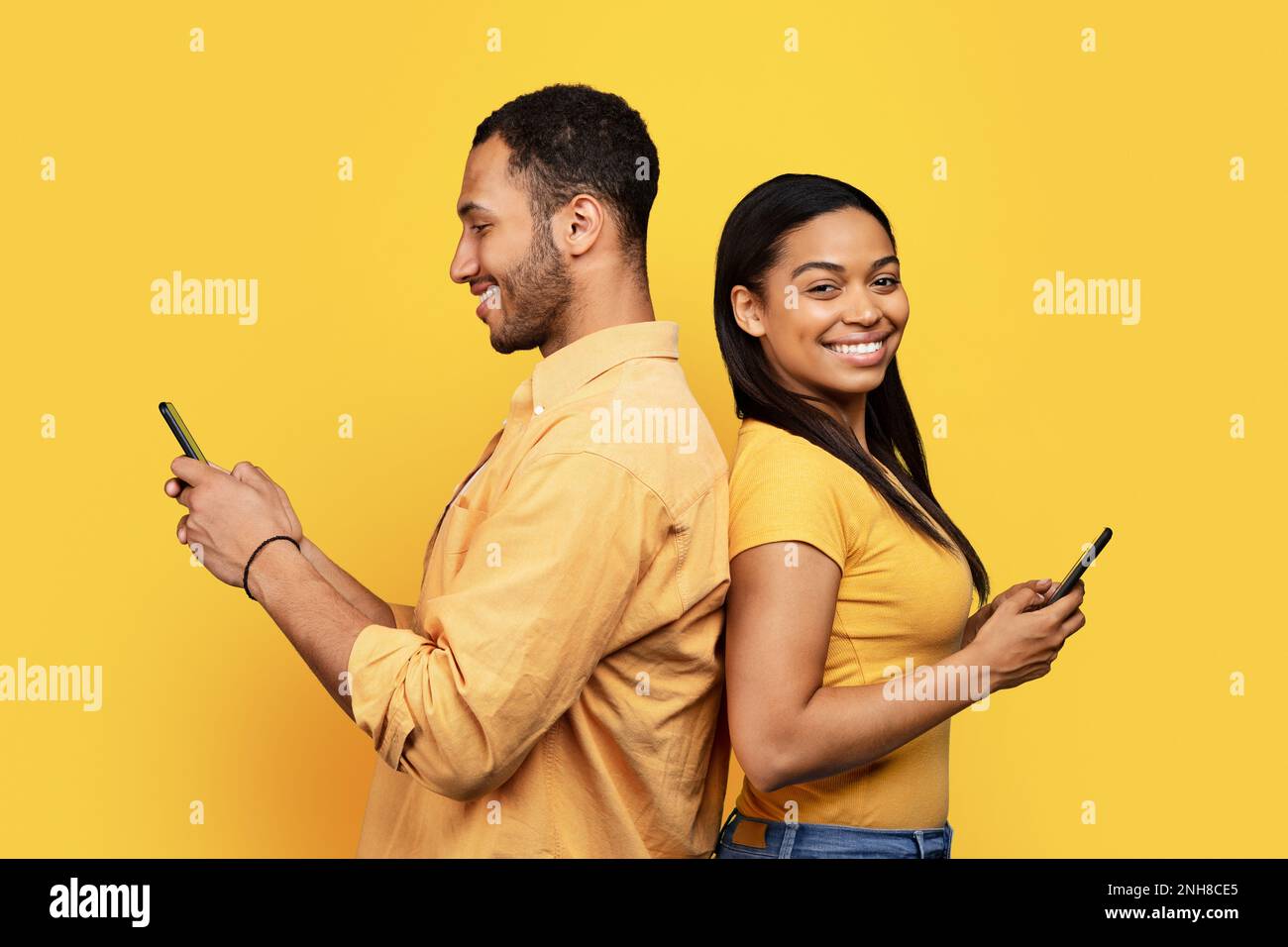 Smiling young african american family back to back, chatting on ...