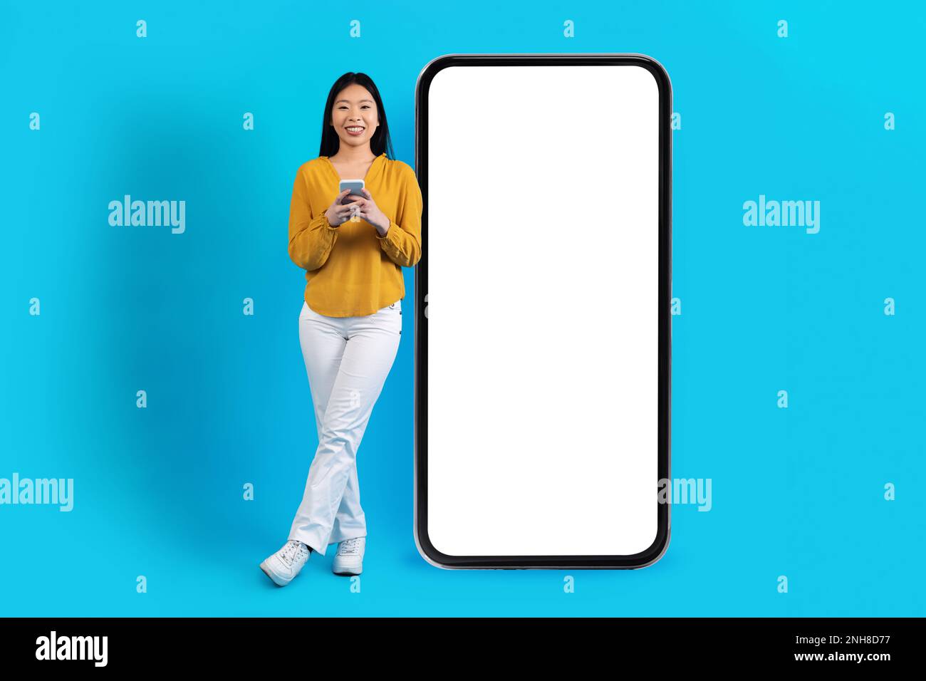 Positive korean lady posing next to big cell phone, mockup Stock Photo ...