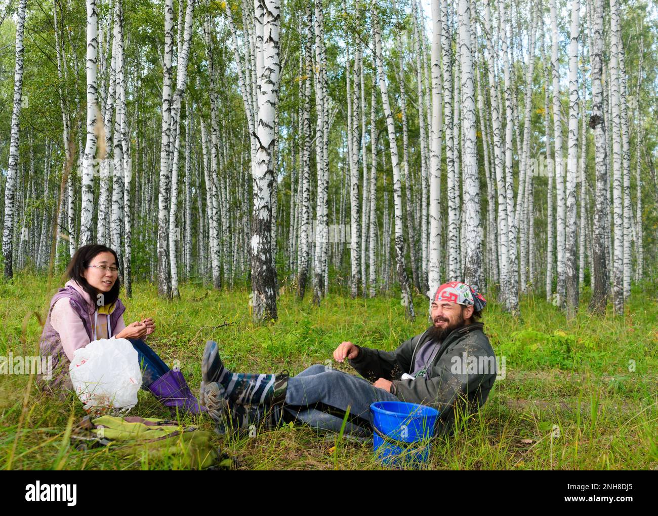 Male and girl smiling thoughtfully sitting in the grass in a field near ...