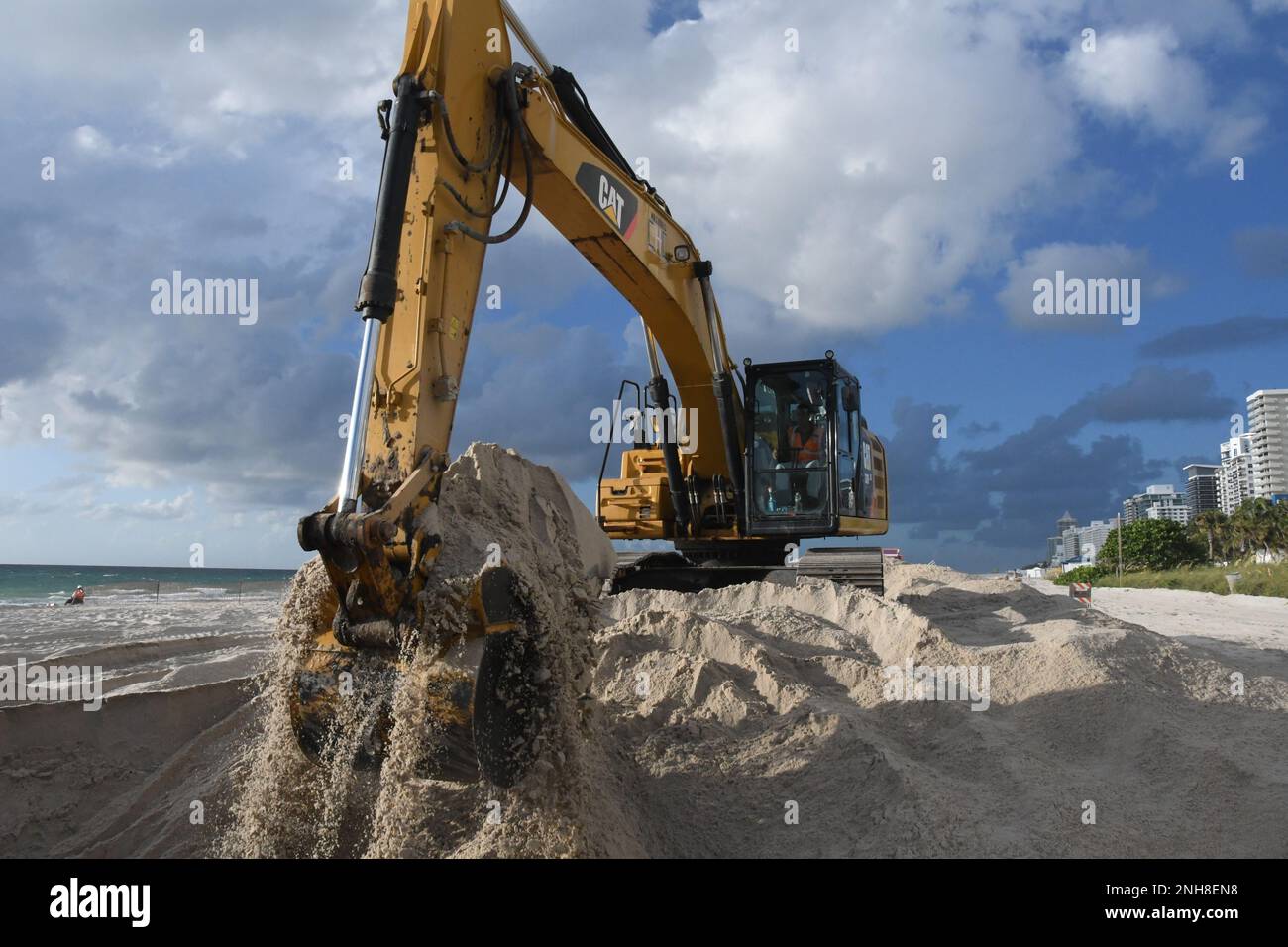 Grab and Go! An excavator grabs a bucket full of beach sand and loads ...