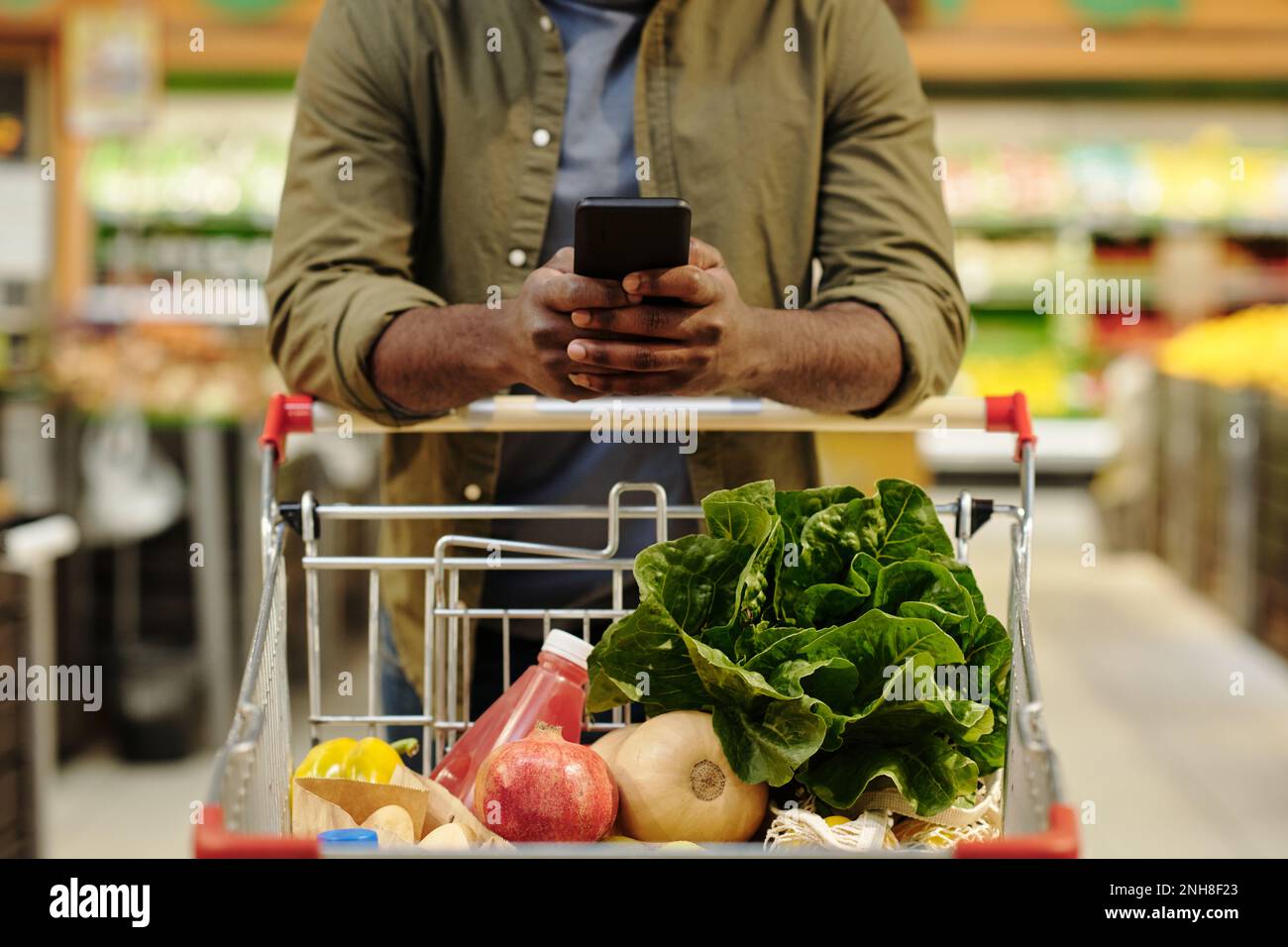 Young African American male consumer pushing shopping cart with fresh ...