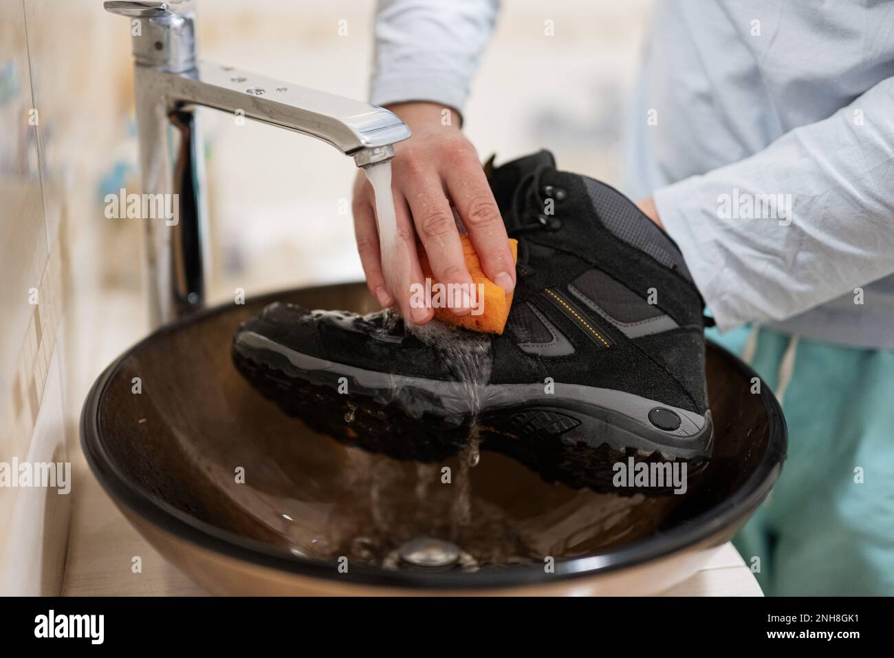 Сleaning the shoes. Man washes boots in the sink Stock Photo - Alamy