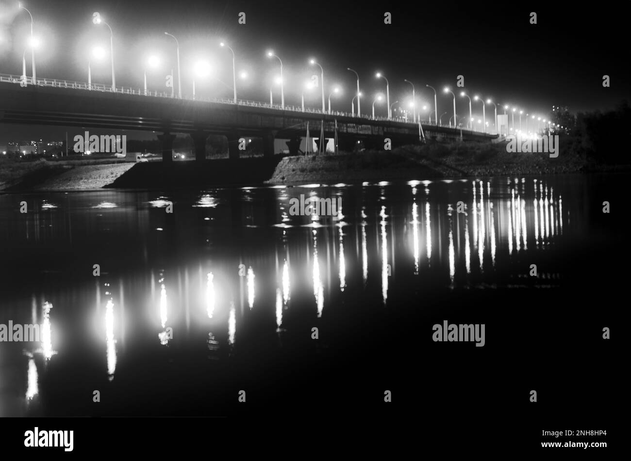 Night road with lanterns going from the arch bridge into a river with ...