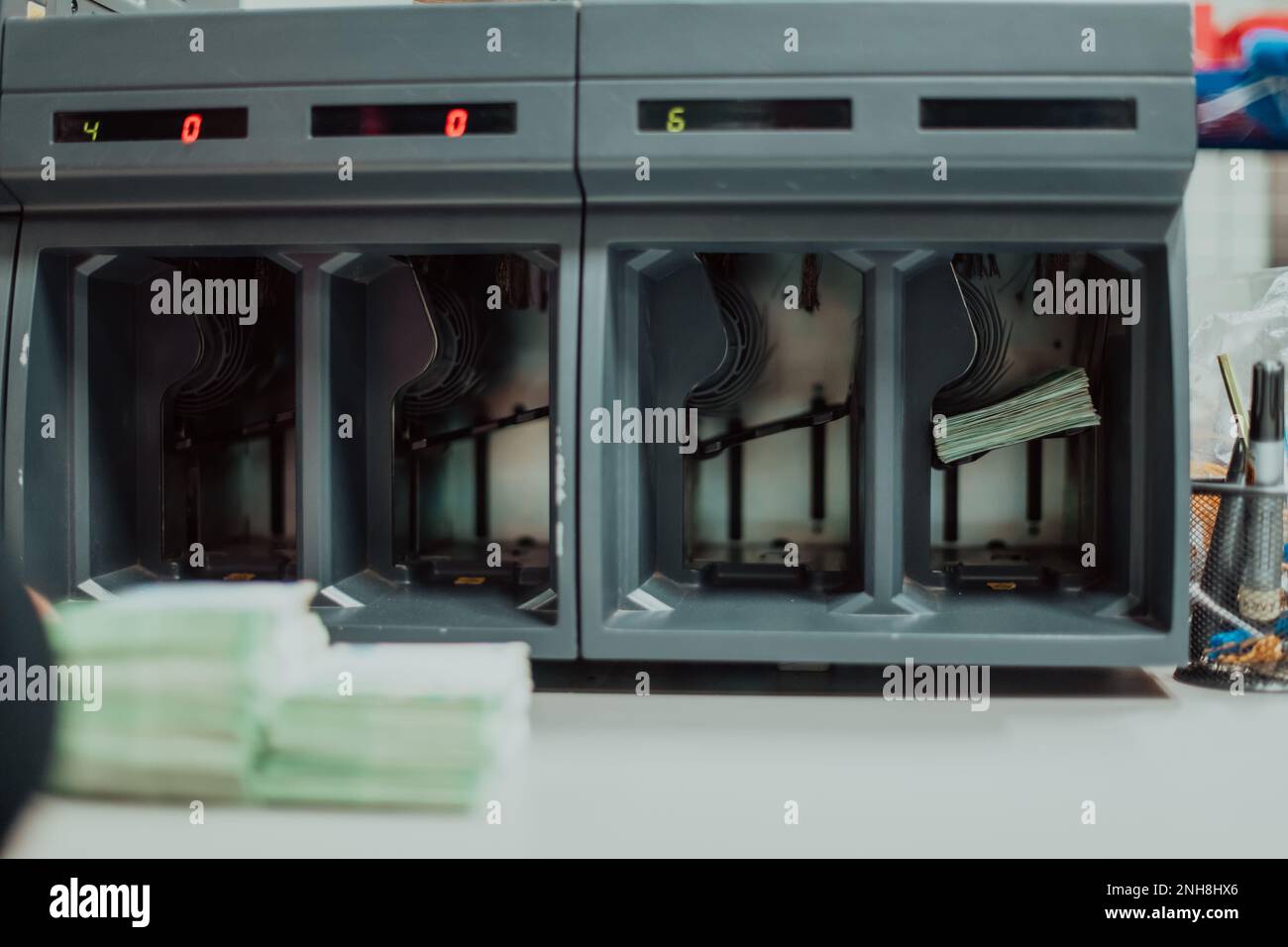 Bank employees using money counting machine while sorting and counting ...