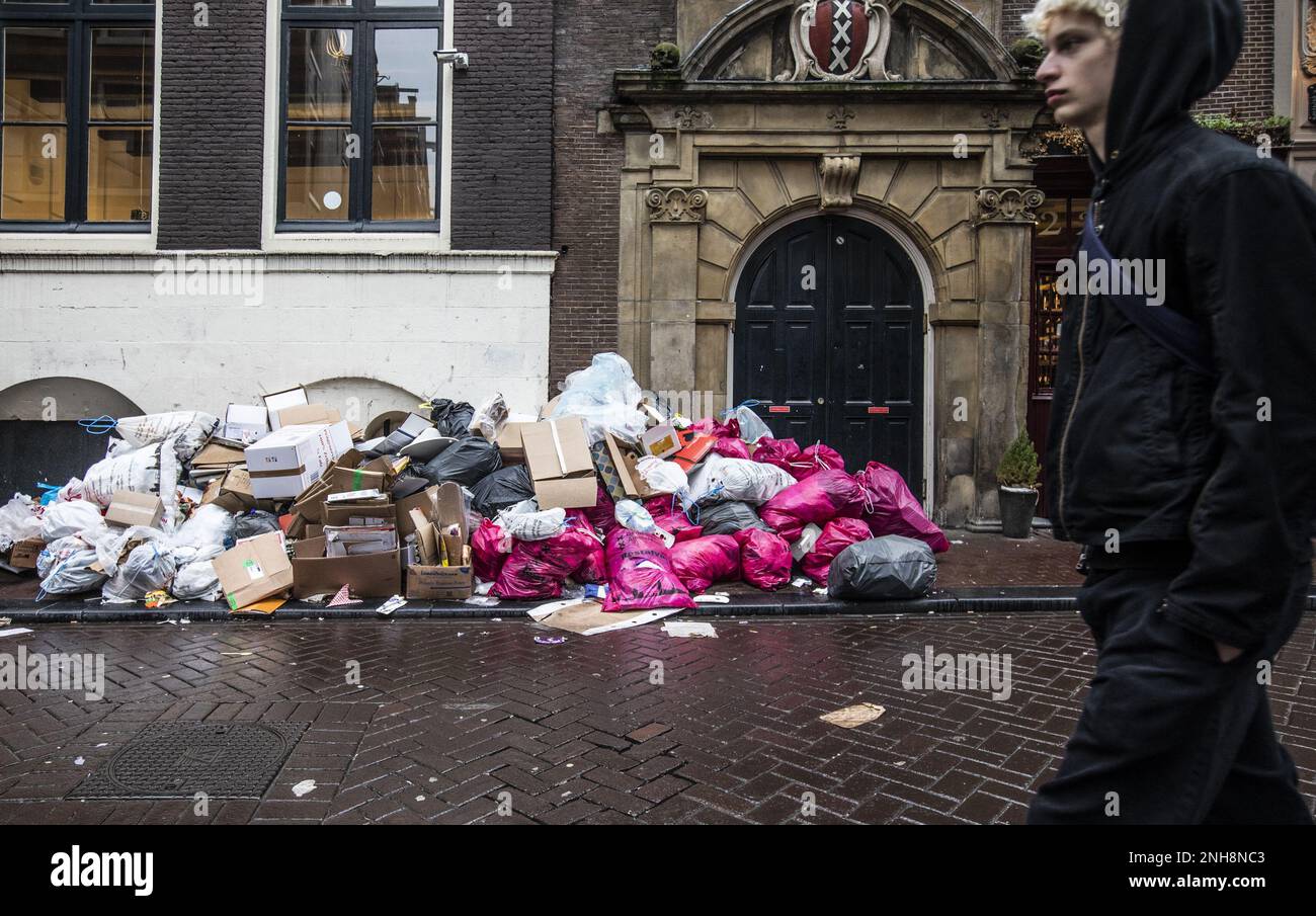 AMSTERDAM - Tourists walk past the garbage during a strike by municipal ...