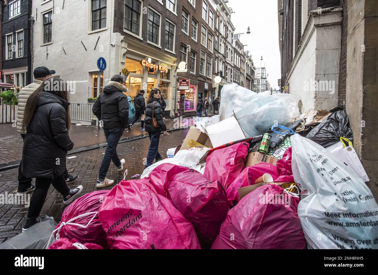 AMSTERDAM - Tourists walk past the garbage during a strike by municipal ...
