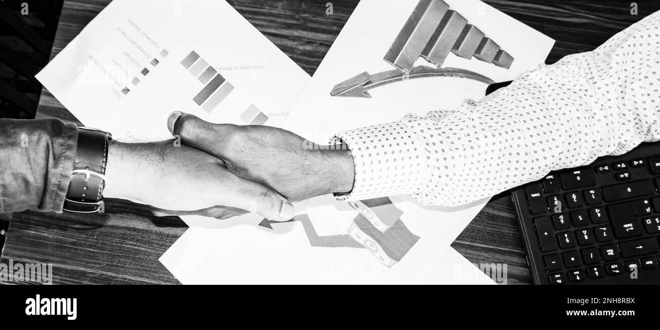 Aerial view of two indian men sitting at the desk with graphs sheets on ... Aerial view of two indian men sitting at the desk with graphs sheets on ...