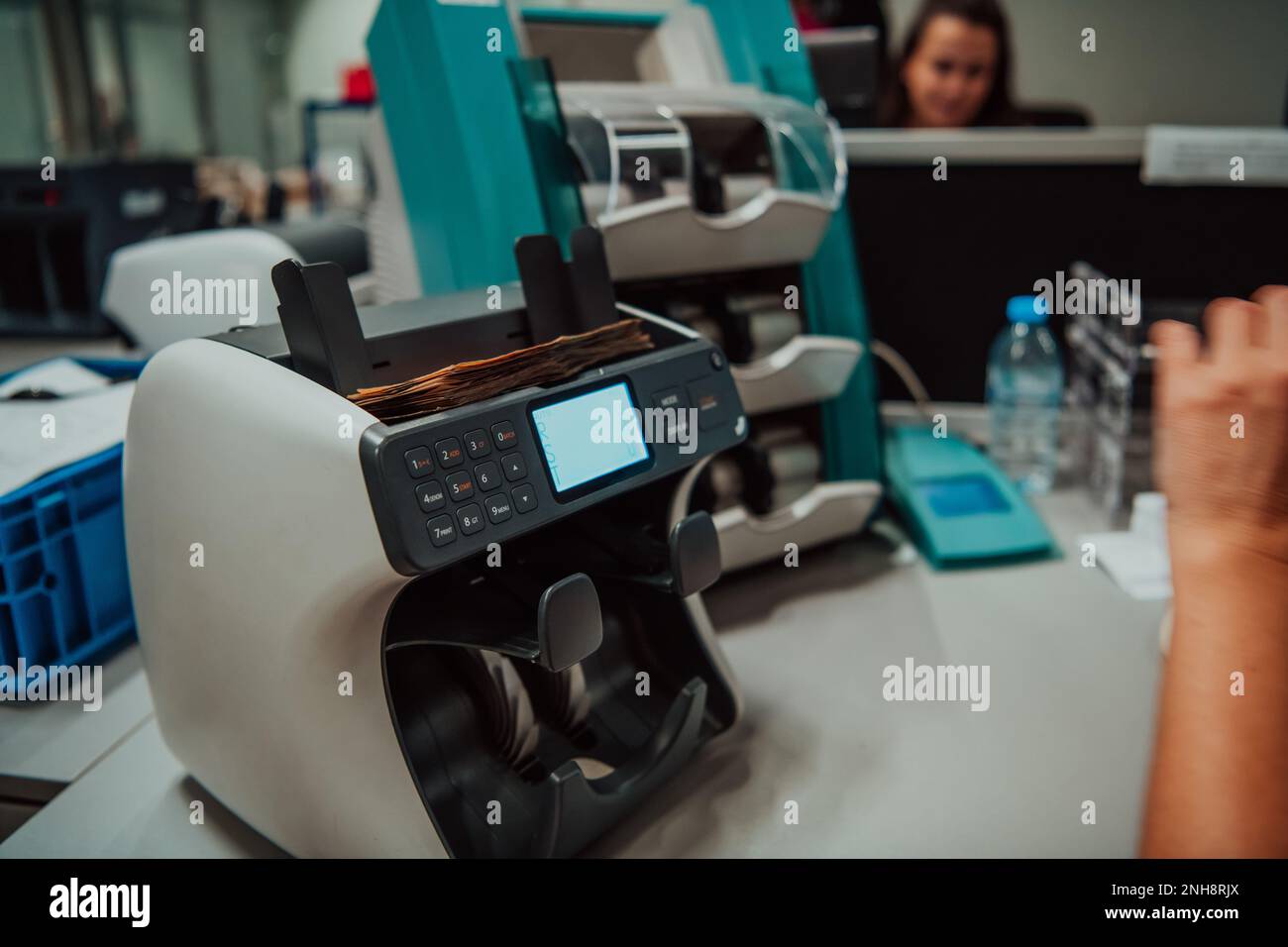 Bank employees using money counting machine while sorting and counting ...