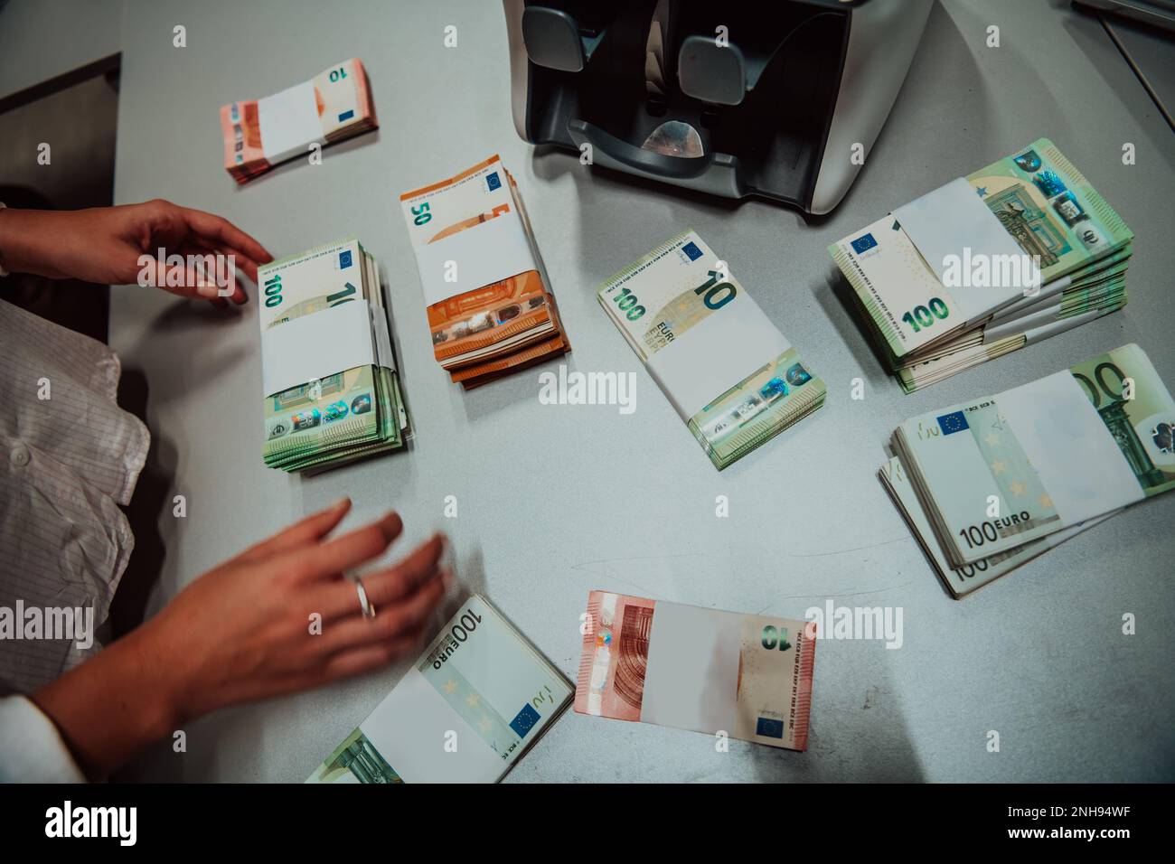 Bank employees using money counting machine while sorting and counting ...