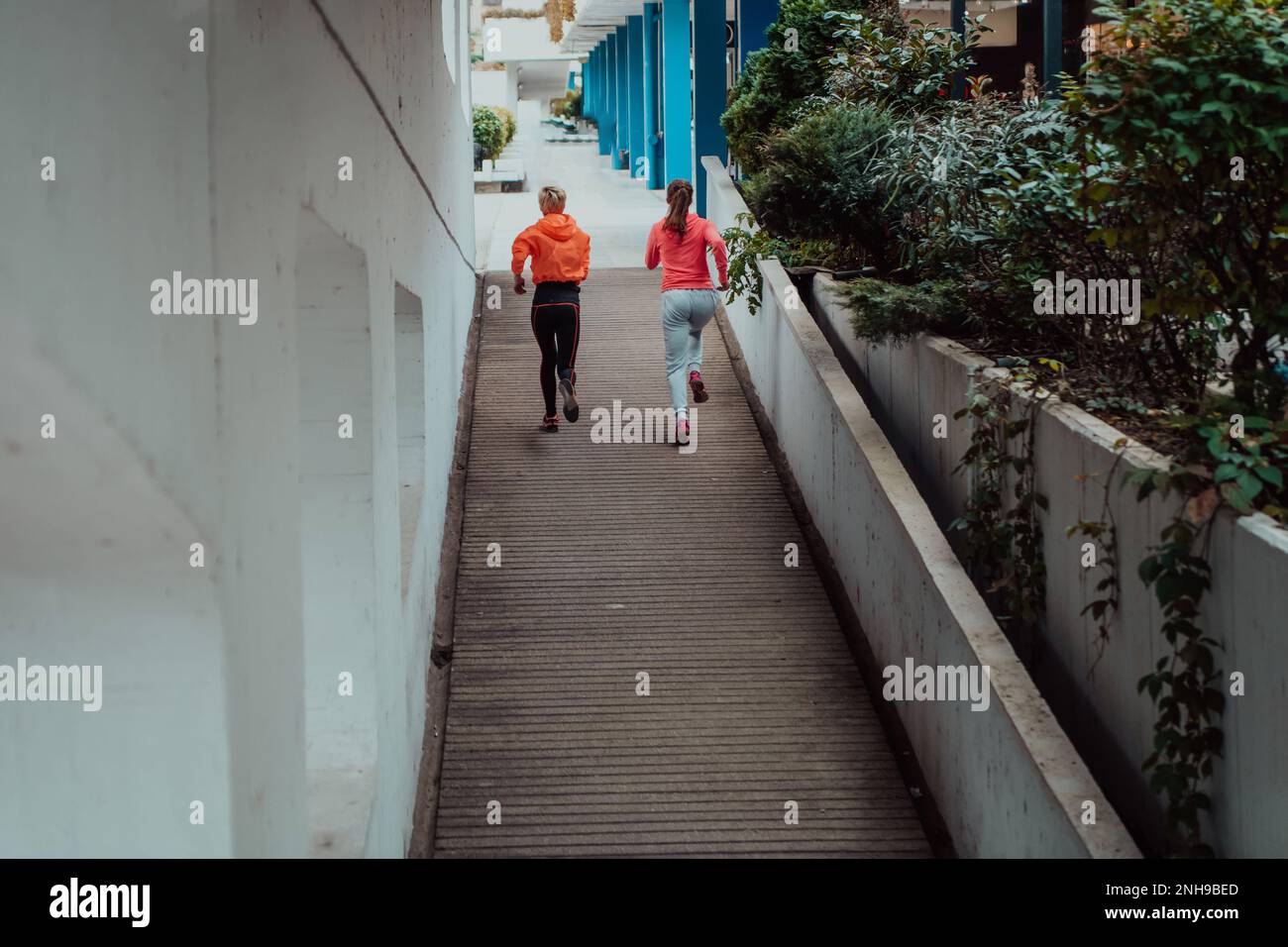 Two women in sports clothes running in a modern urban environment. The ...