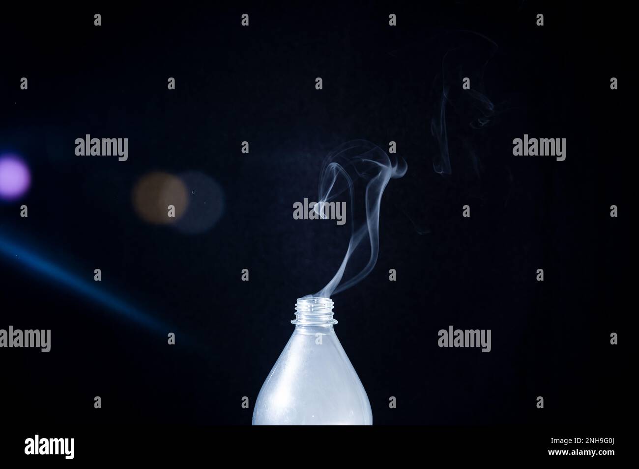 Smoke coming out of a plastic bottle against a black background with ...