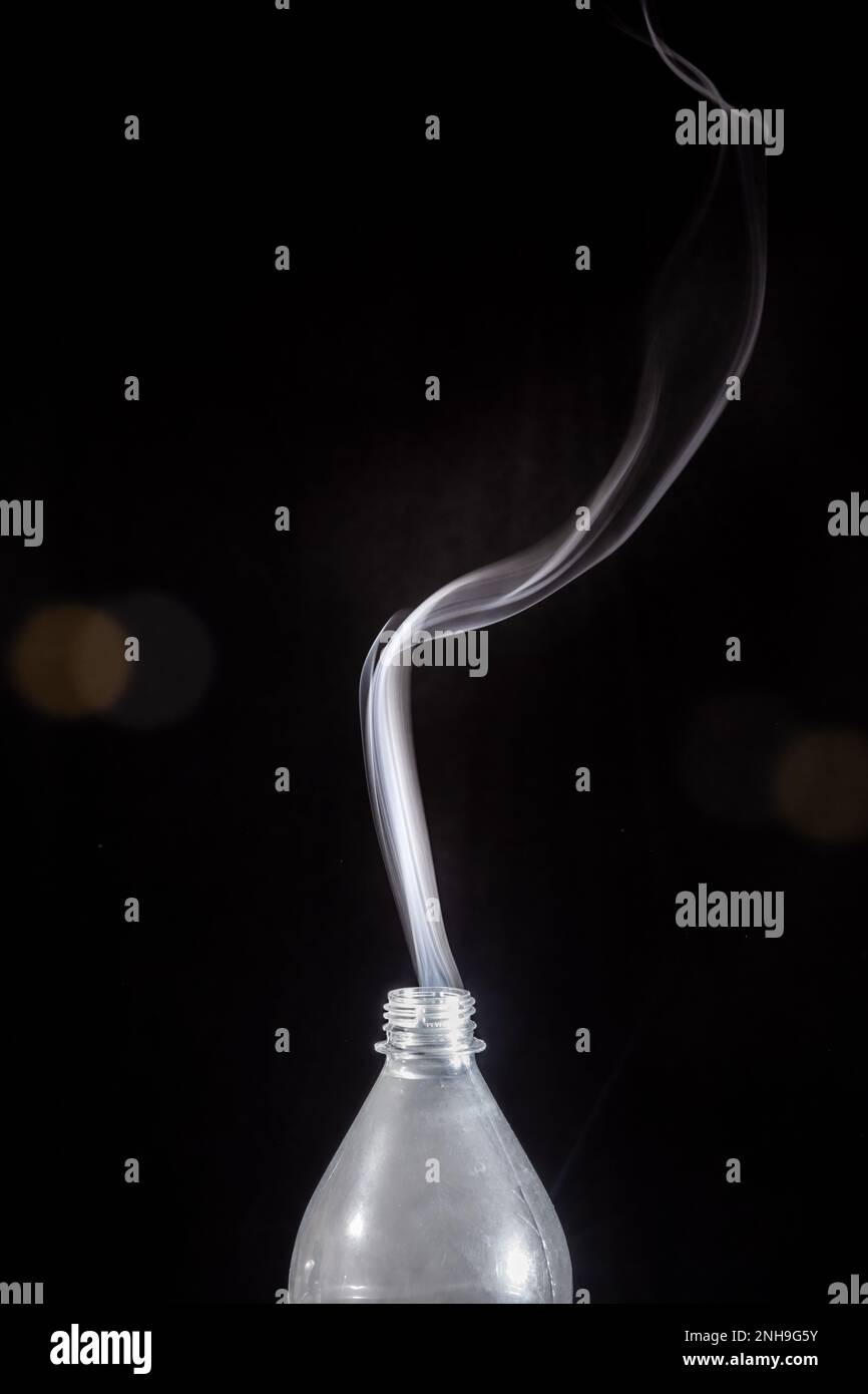 Smoke coming out of a plastic bottle against a black background with ...