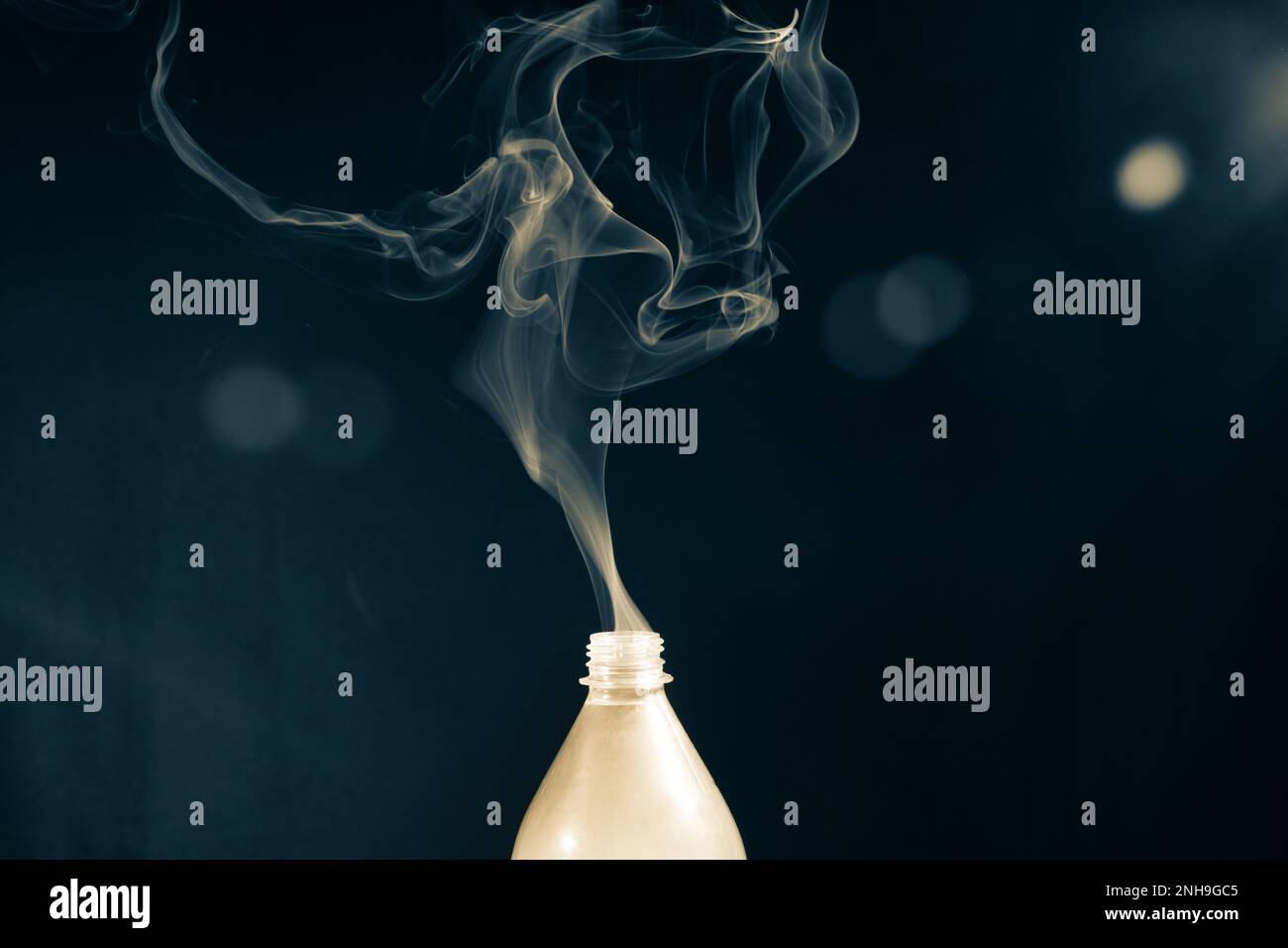 Smoke coming out of a plastic bottle against a black background with ...