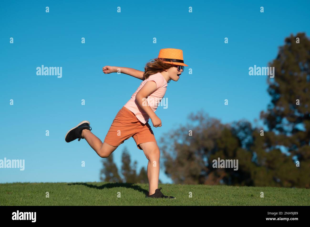 Kid boy running on green grass near blue sky in summer park. Healthy ...