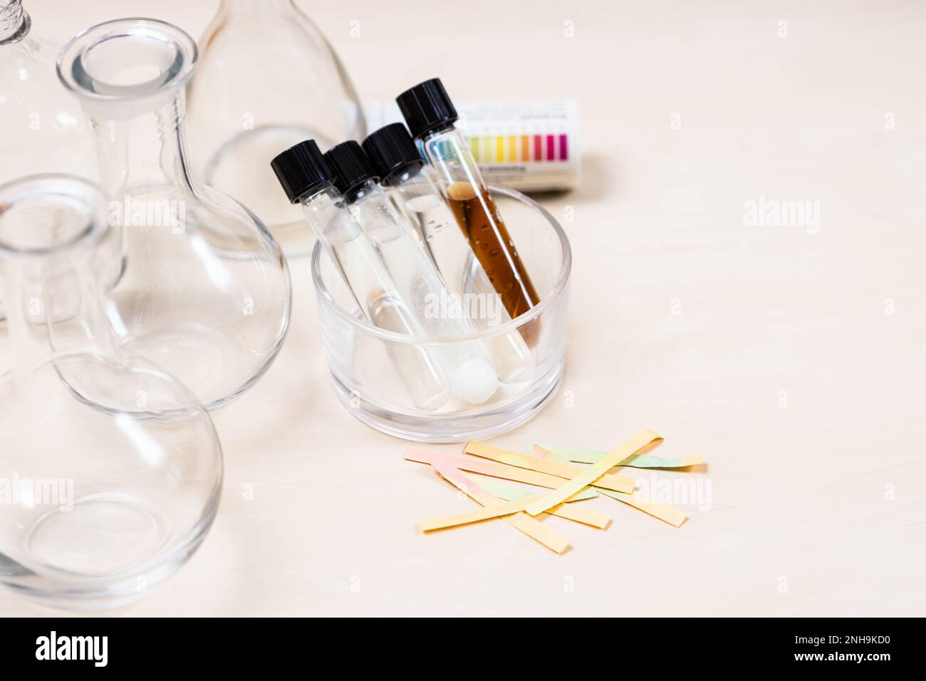 test tubes with liquids and solutions, flasks and indicator papers on ...