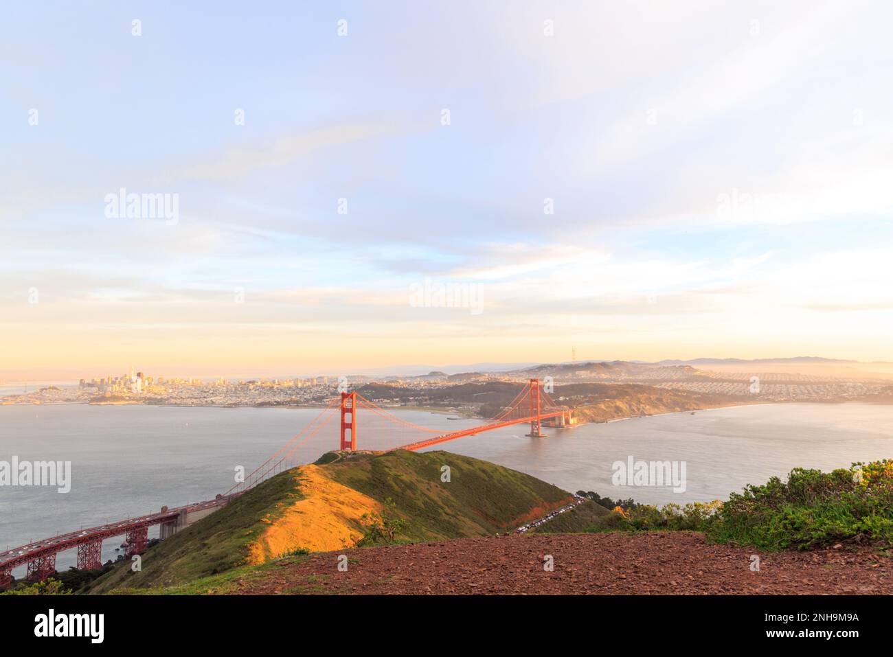 Red suspension bridge with city of San Francisco in distance at golden ...