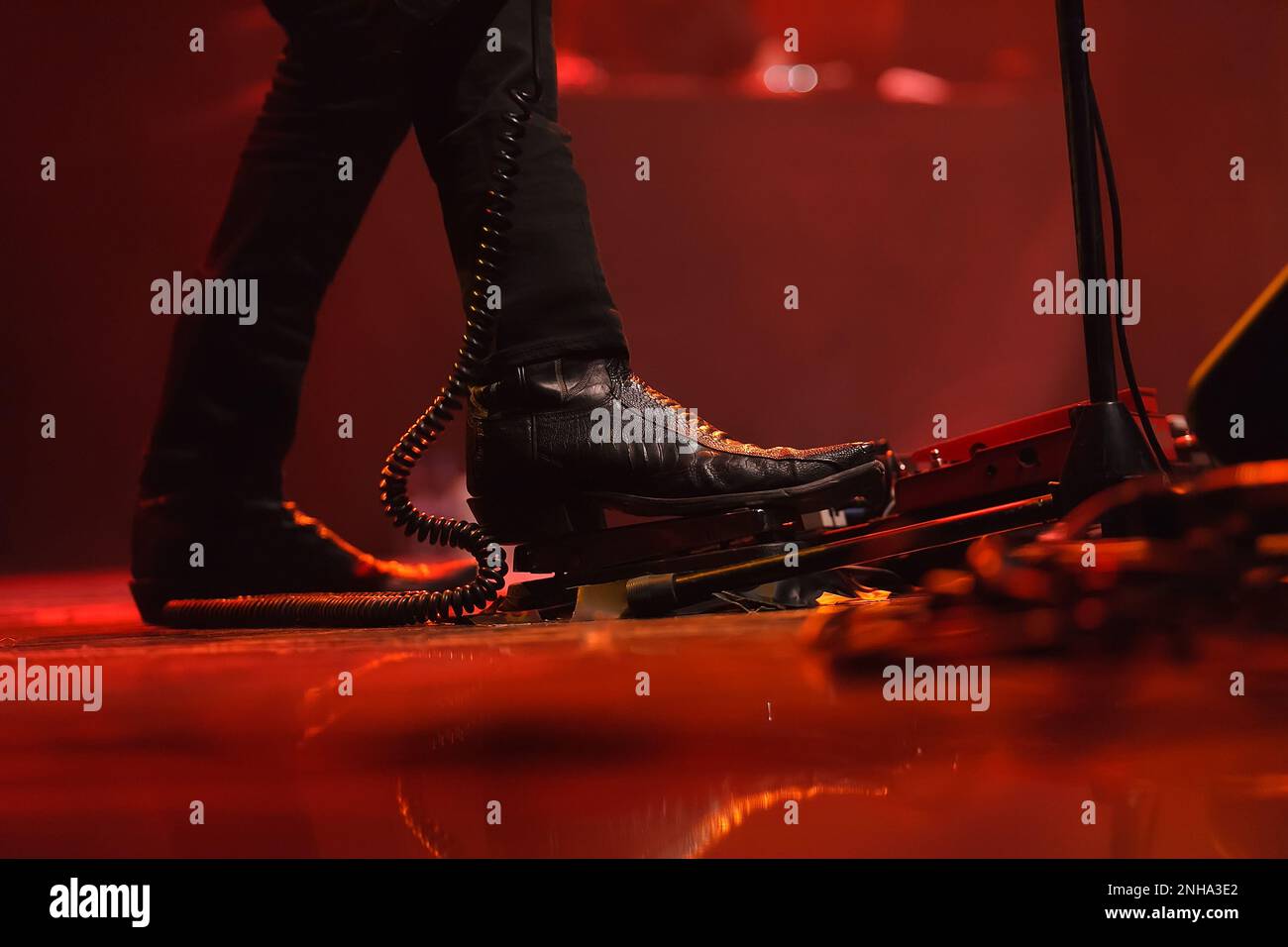 Cool rock singer in stylish leather boots playing on electric guitar ...