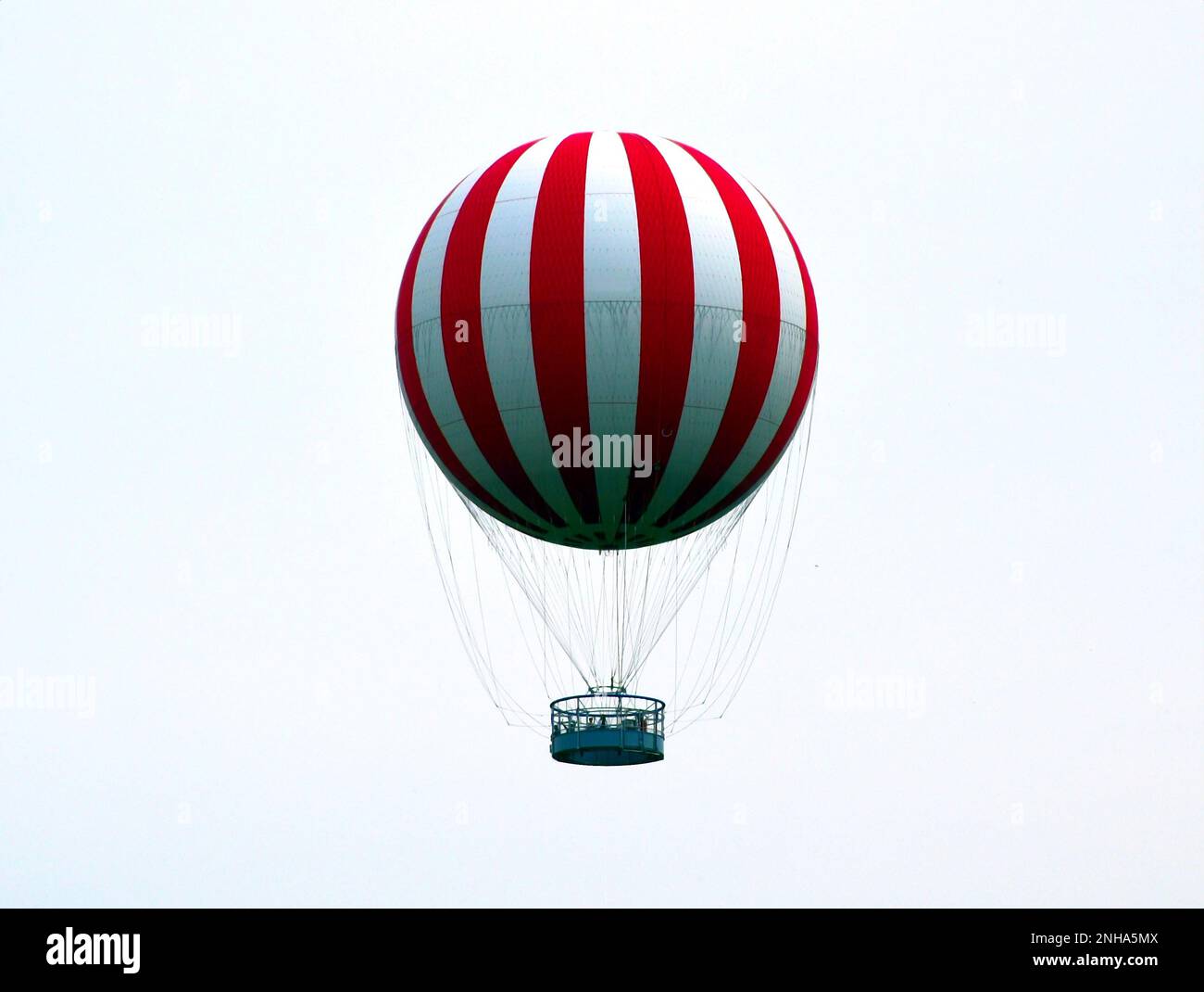 isolated red and white adventure balloon up high. suspended basket and ...