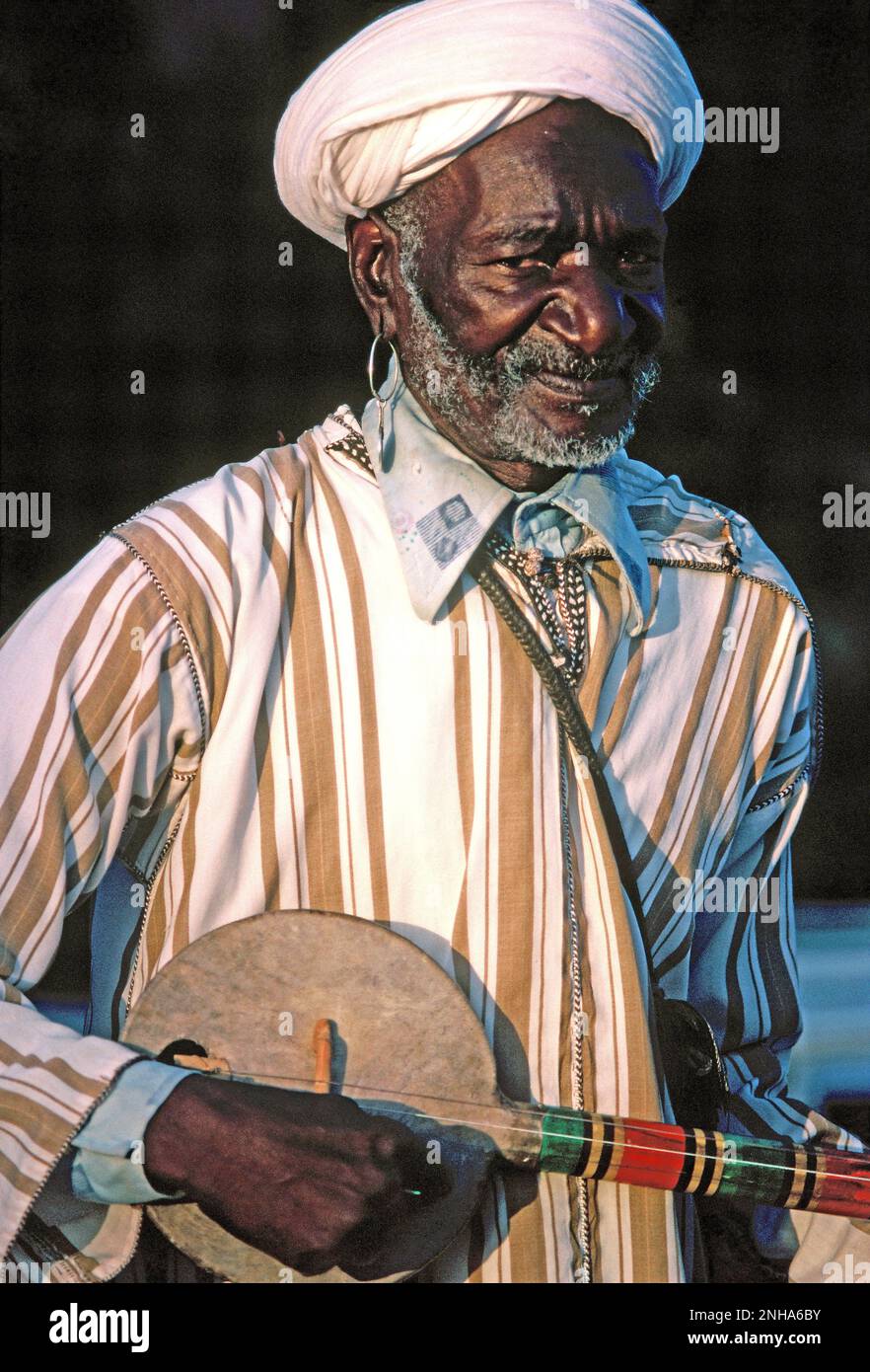 Morocco. Marrakech. Gnawa tribal man. Street musician playing guembri ...